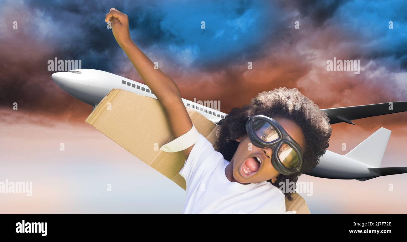 African american boy with cardboard wings and goggles flying and ...
