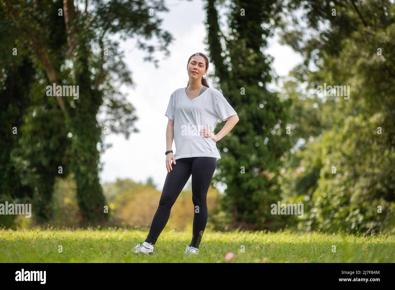 A young fit woman in sports clothes relax at the summer park. Wellness ...