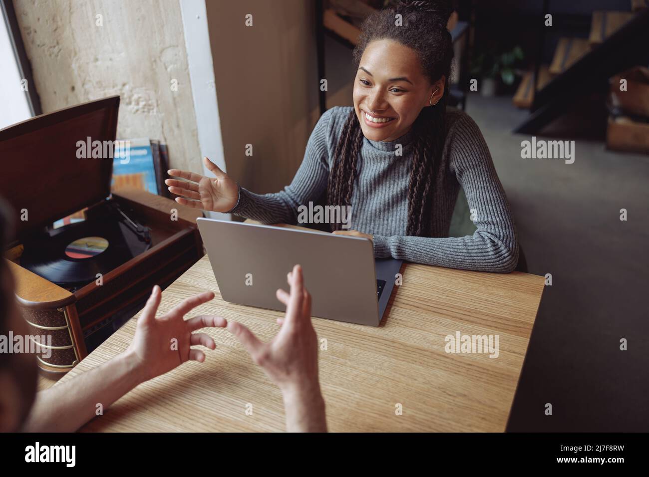 Young joyful woman with laptop computer having business meeting in cafe ...