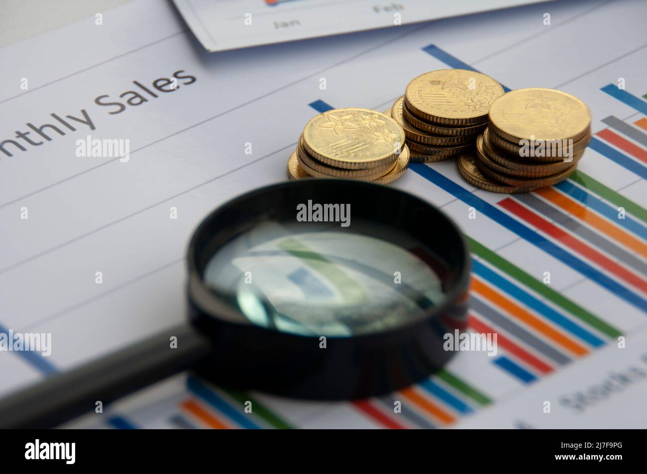 Analysis of data, chart and graphs with magnifying glass and gold coins ...