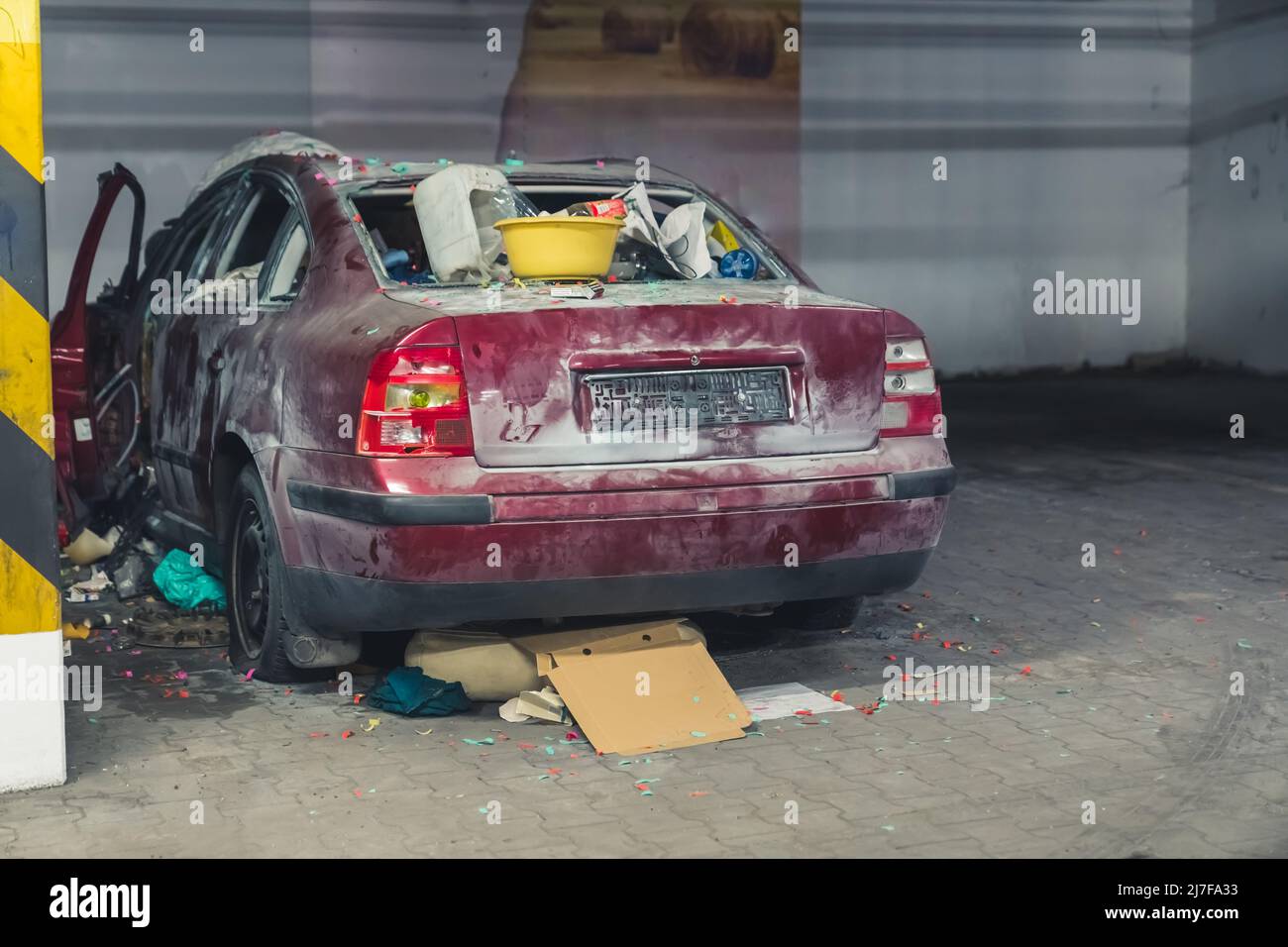 photo of a destroyed car with trash in the underground parking lot full ...