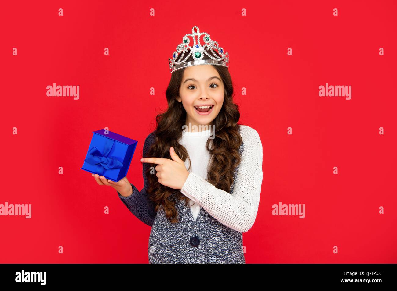 surprised child in queen crown. princess in tiara point finger on box ...