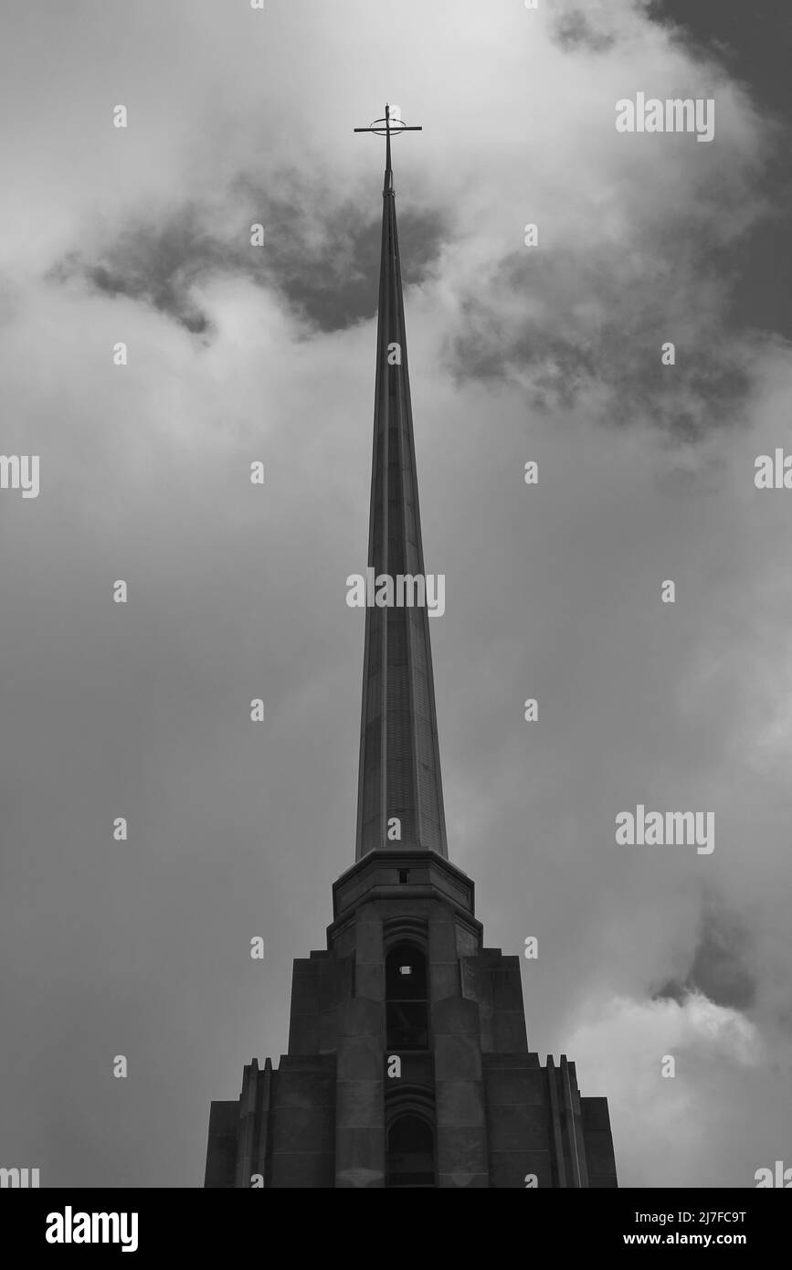A very tall steeple with a Christian cross on top reaching for the ...