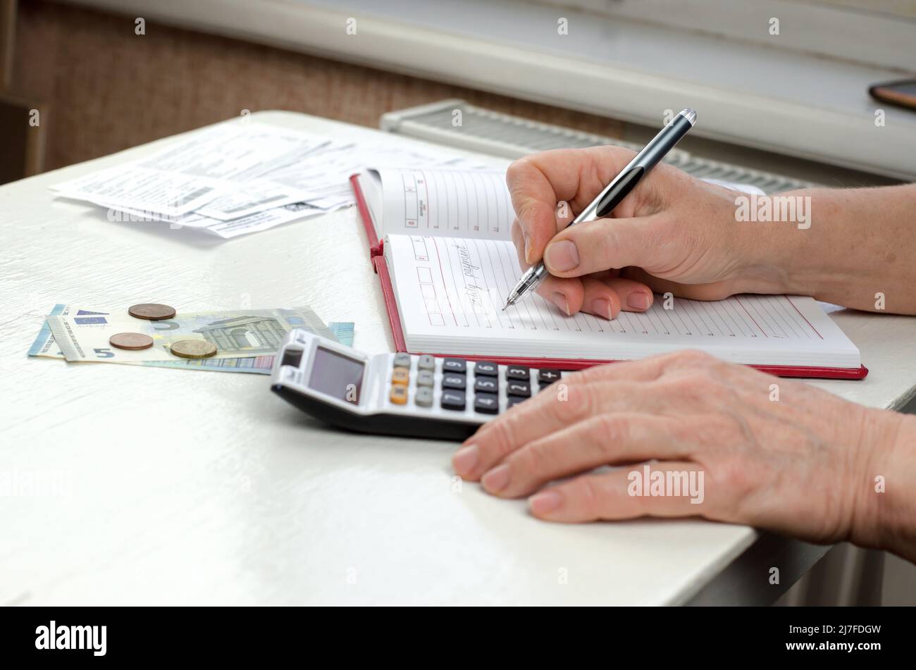 Close-up of an elderly woman's hands holding a pen working on a utility ...