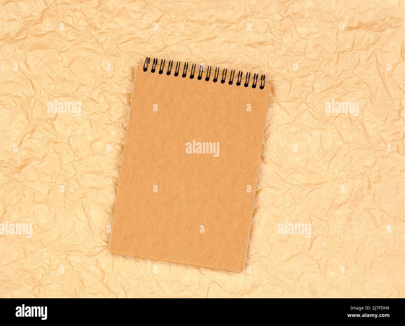 Brown notepad with a craftpaper on a background of beige crumpled ...