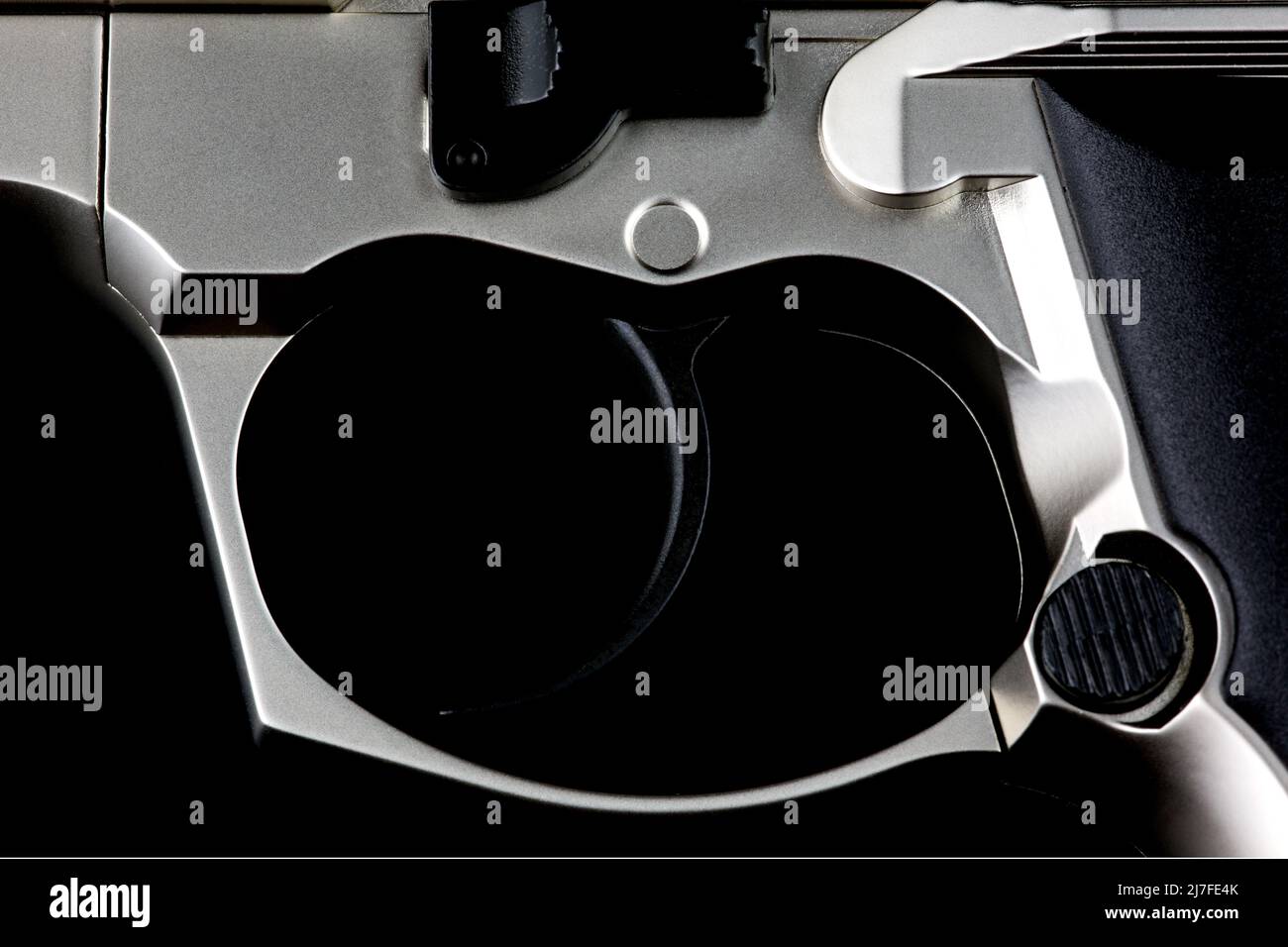 Trigger section of semi automatic pistol against a balck background ...