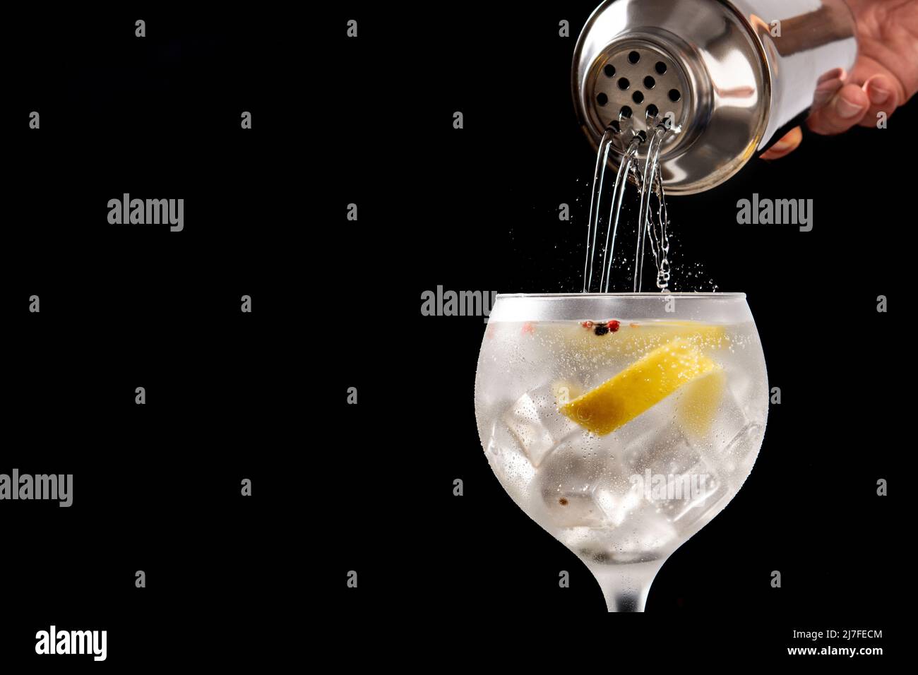 Pouring gin tonic drink into a glass on black background Stock Photo - Alamy
