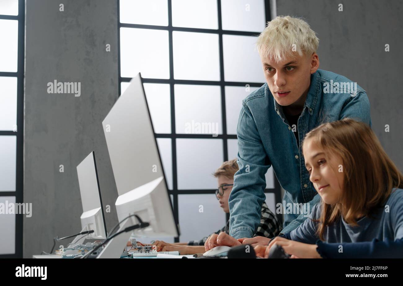 School kids with help of teacher using computer in classroom at school ...