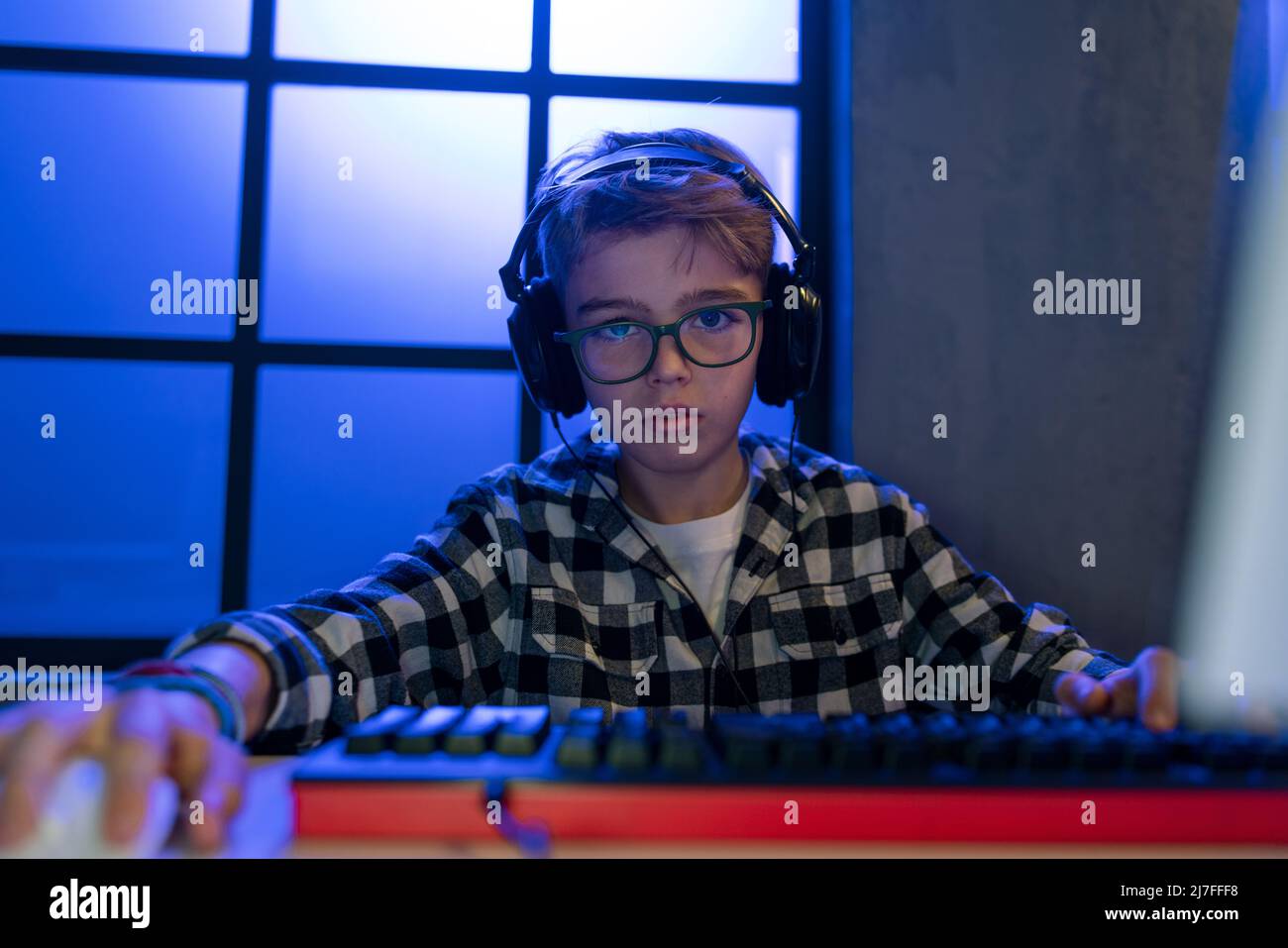 Young gamer boy with headphones playing computer video game Stock Photo ...