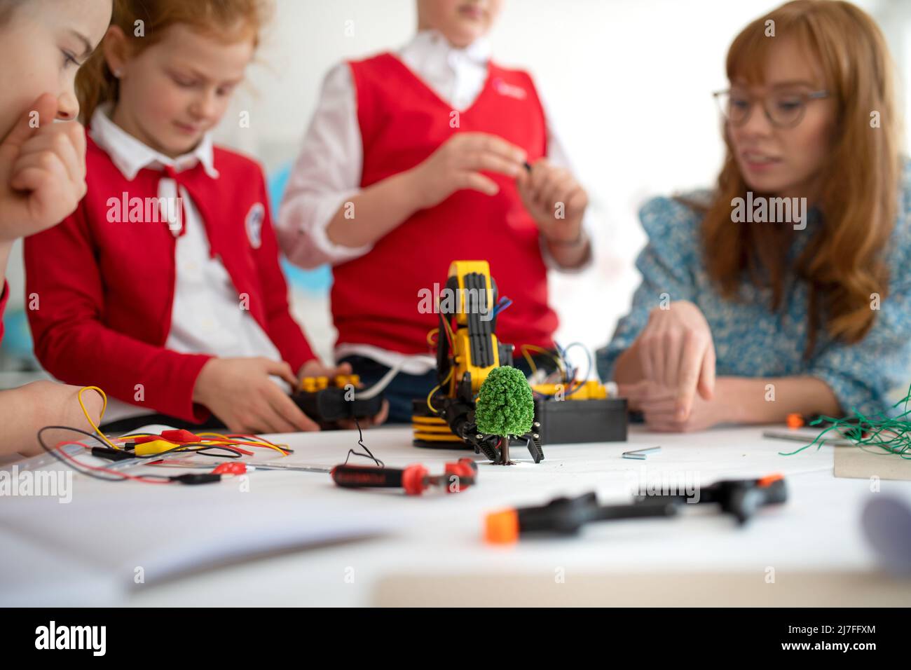 Group of kids with young science teacher programming electric toys and ...