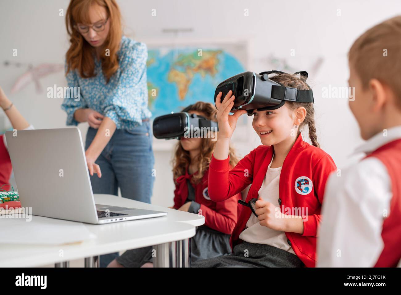 Happy schoolchildren wearing virtual reality goggles at school in ...
