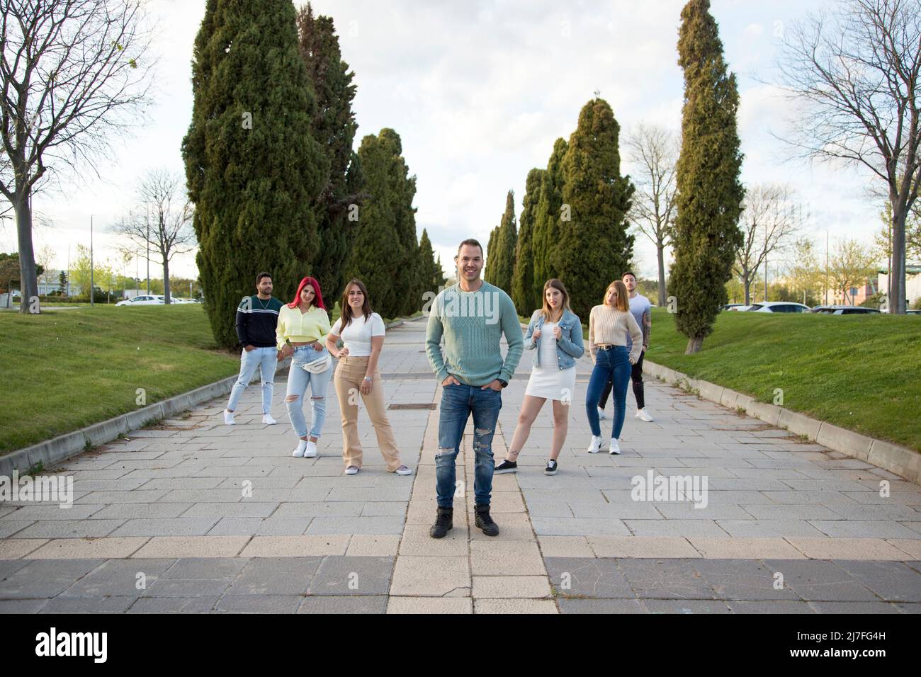 group of seven friends posing separately looking at camera outdoors ...