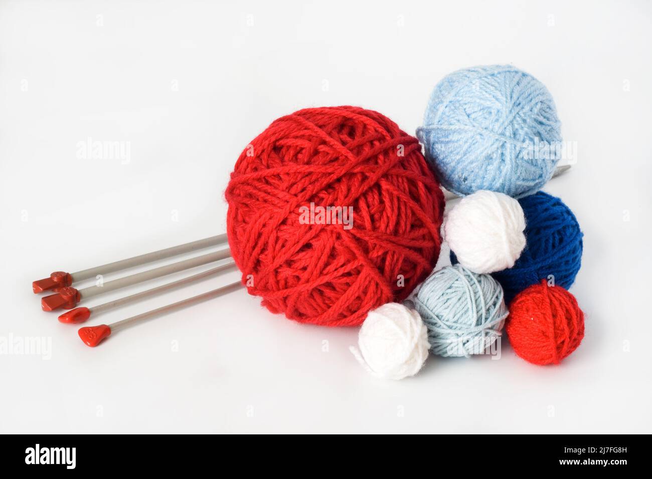 Colorful balls and needles for knitting lying on a white background ...