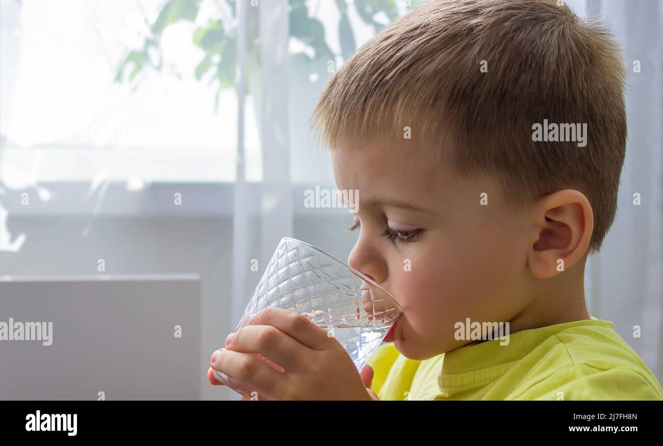 The boy drinks water from a glass. Pure water. Summer. selective focus ...
