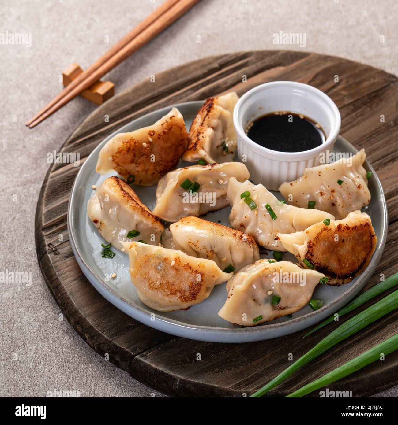 Taiwanese and Japanese Pan-fried gyoza dumpling jiaozi food in a plate with soy sauce on gray ...