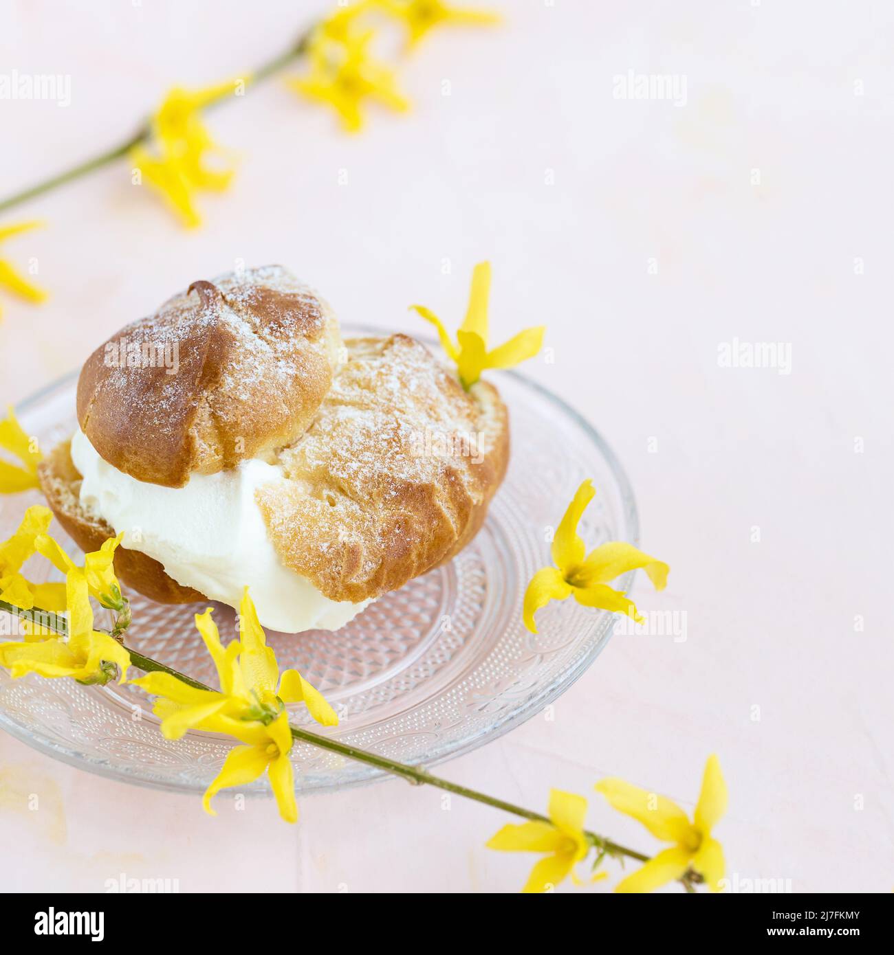 Choux Bun with whipped cream and sugar powder on top on glass plate ...