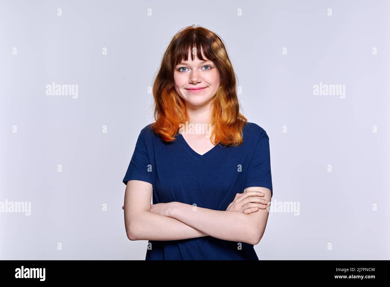Portrait of young red-haired female looking at camera on light studio ...