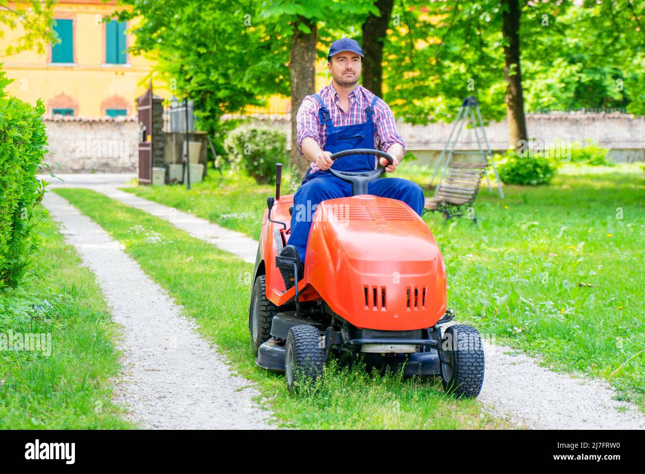 One gardener driving riding lawn mower garden Stock Photo - Alamy