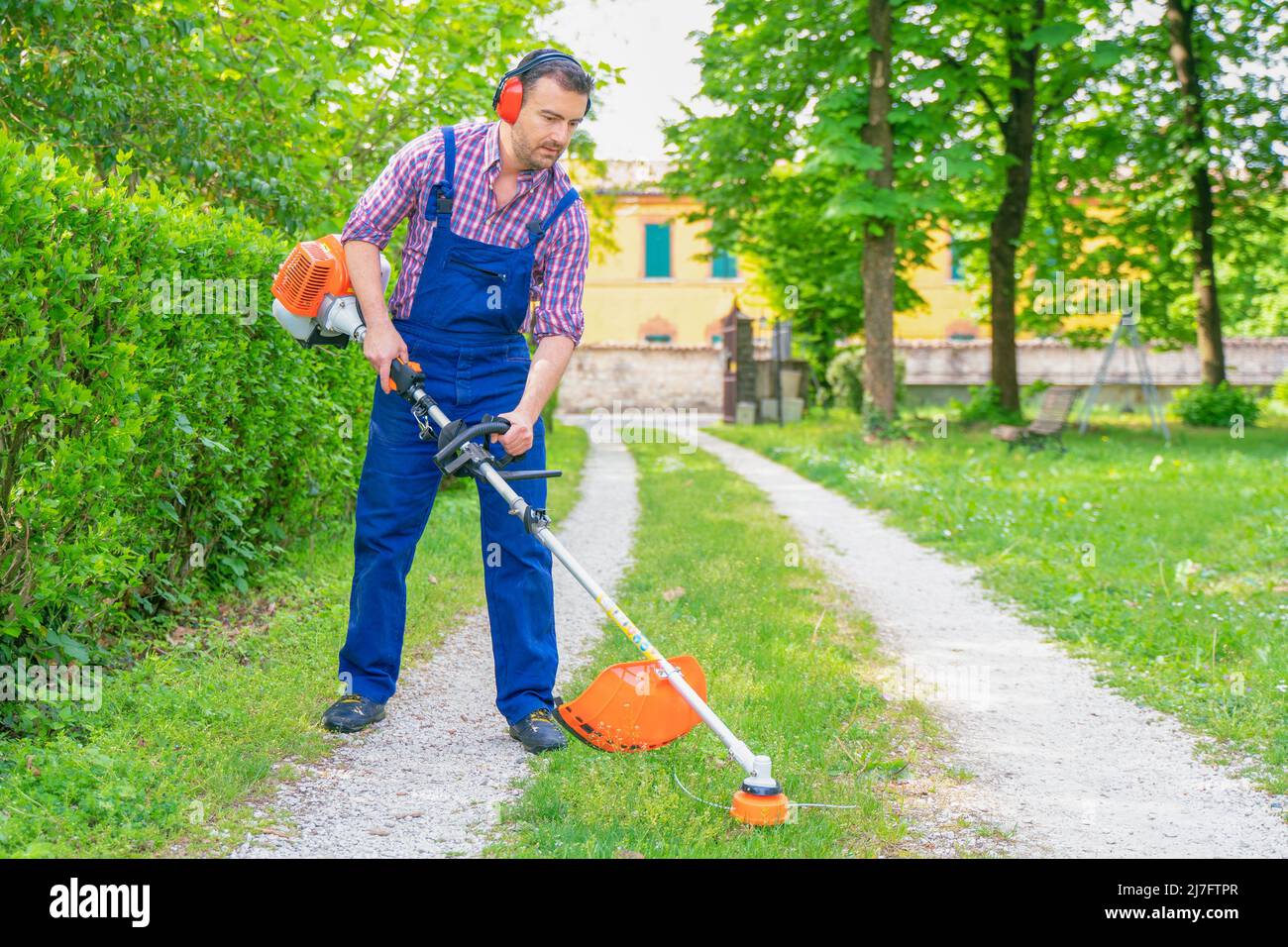 One man working in garden and mowing grass using brush cutter Stock ...