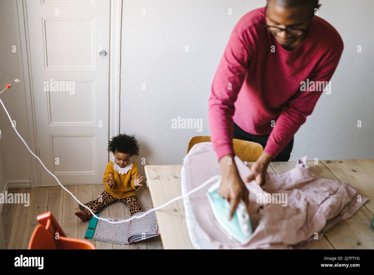 Father ironing clothes while daughter playing on floor Stock Photo - Alamy