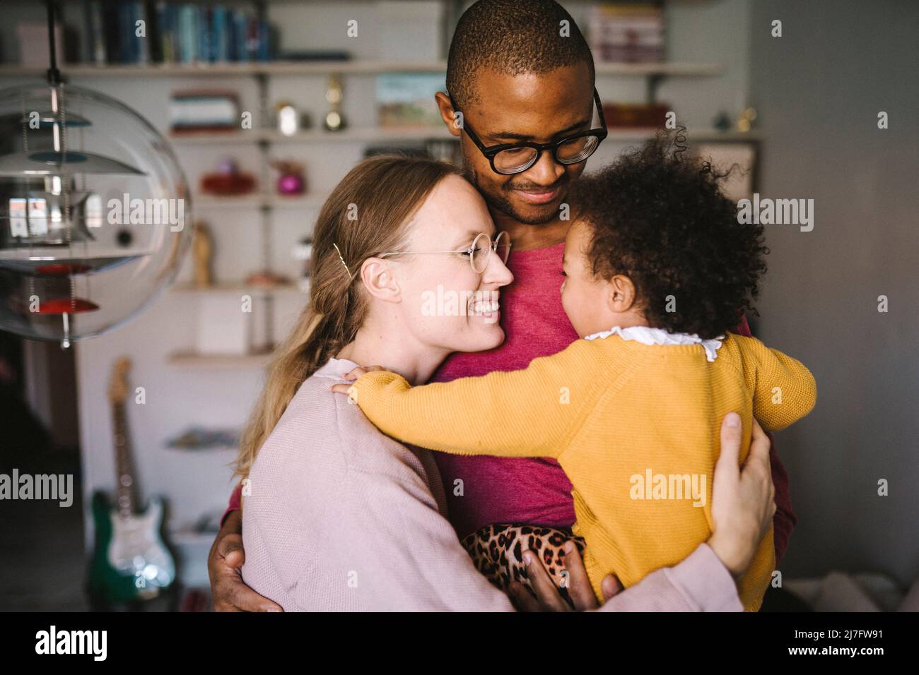 Young parents hugging daughter at home Stock Photo - Alamy