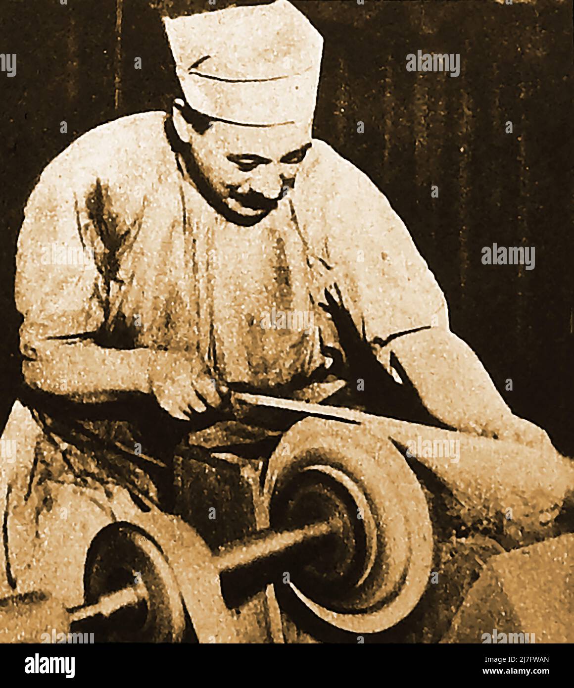 WWI A worker at Wilkinson Sword factory, England, Grinding the blade on ...