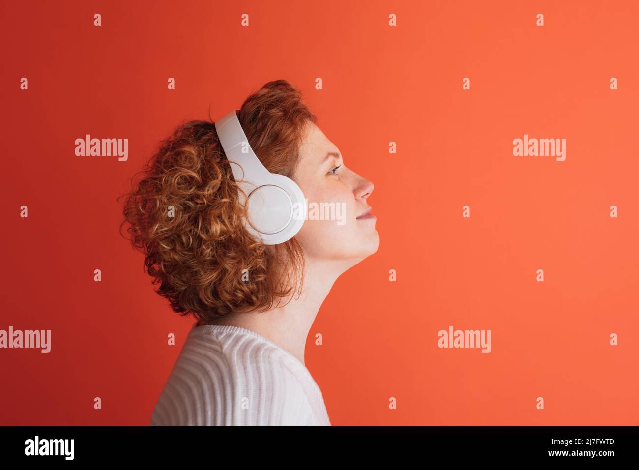 Side view portrait of red-haired woman calmly listening to music in ...