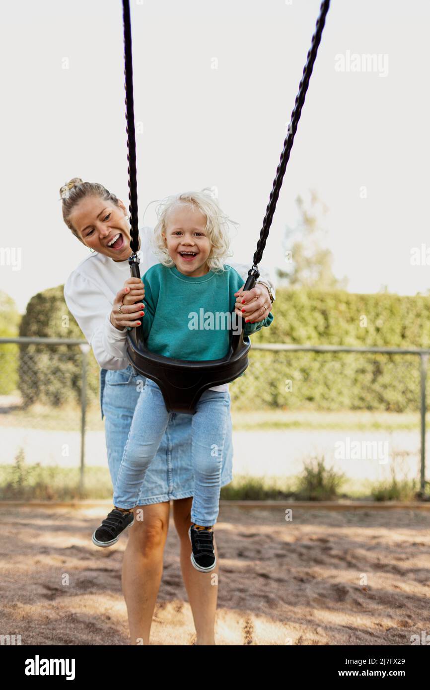Happy mother swinging child at playground Stock Photo - Alamy
