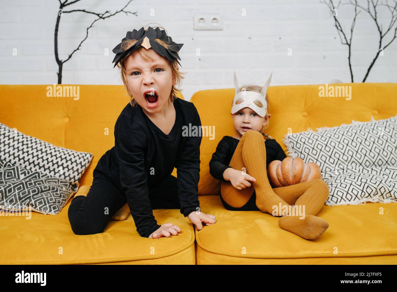 Playful awkward preschooler kids dressed for halloween on a yellow ...