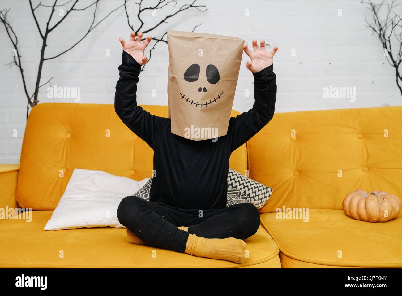 Spooky kid wearing a paper bag over his head, a scary face is drawn on ...