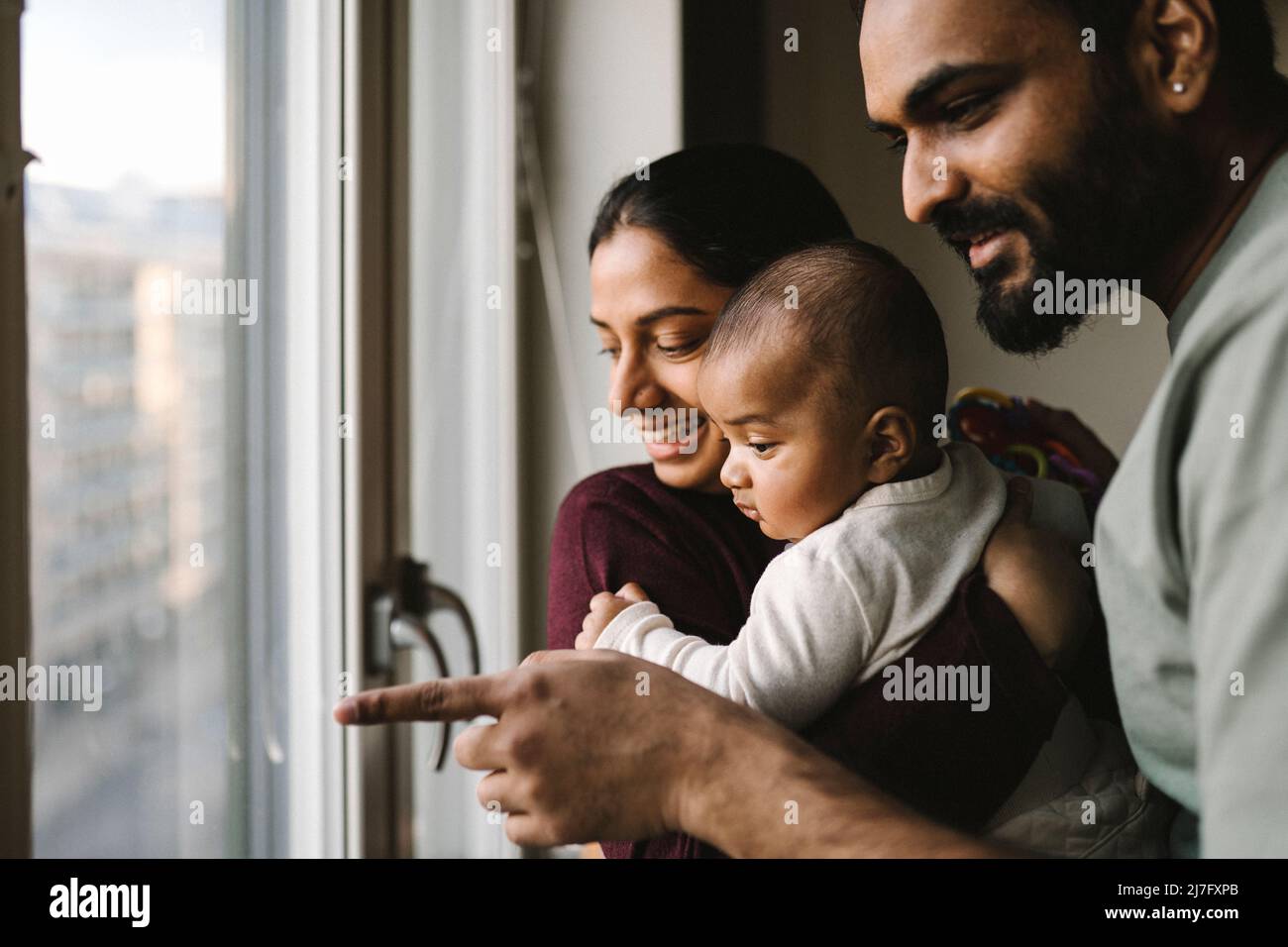 Father and mother with baby looking through window Stock Photo - Alamy