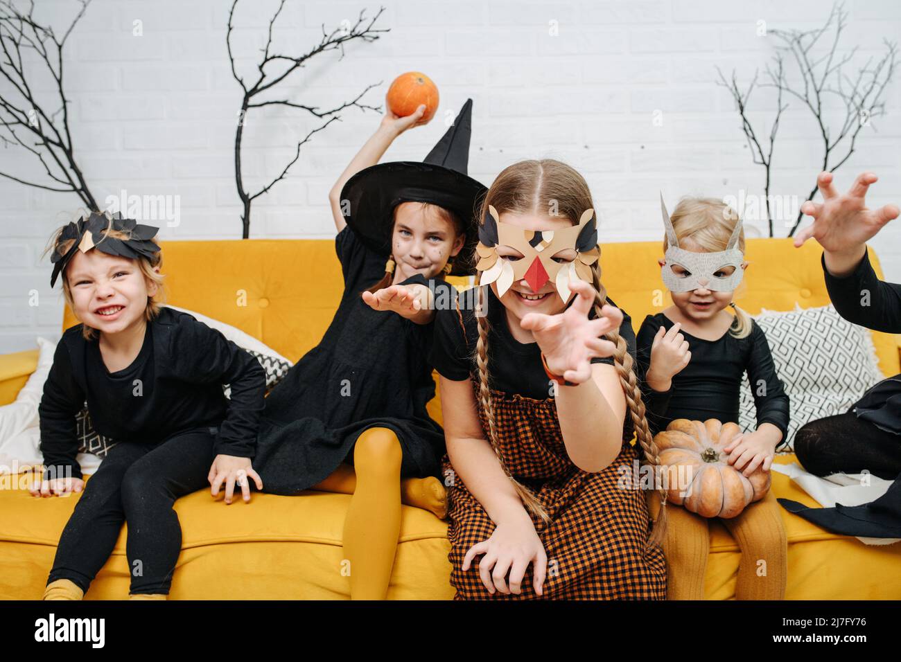 Cute little kids dressed for halloween party sitting on a yellow couch ...