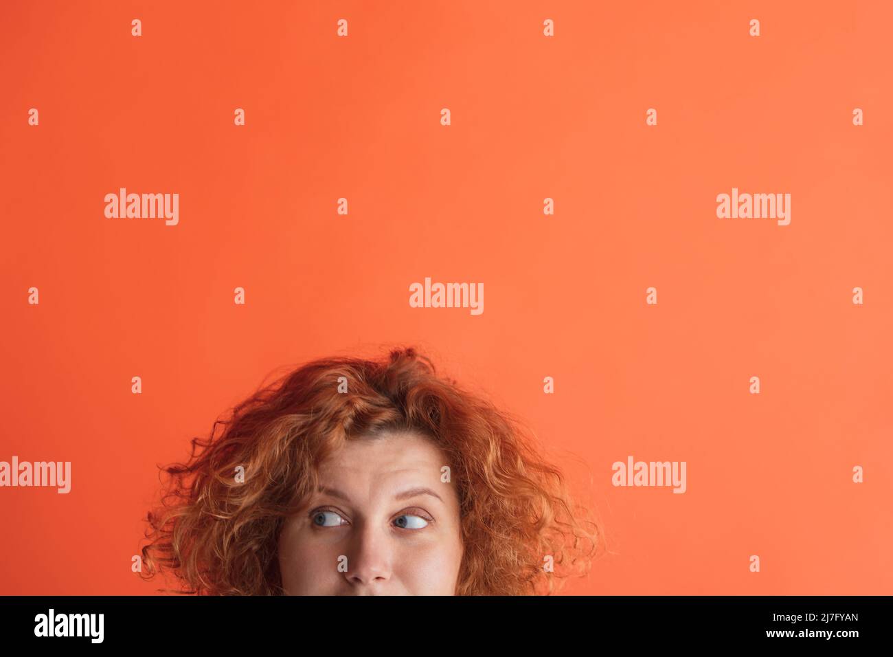 Half-faced portrait of red-haired woman posing, isolated over red ...