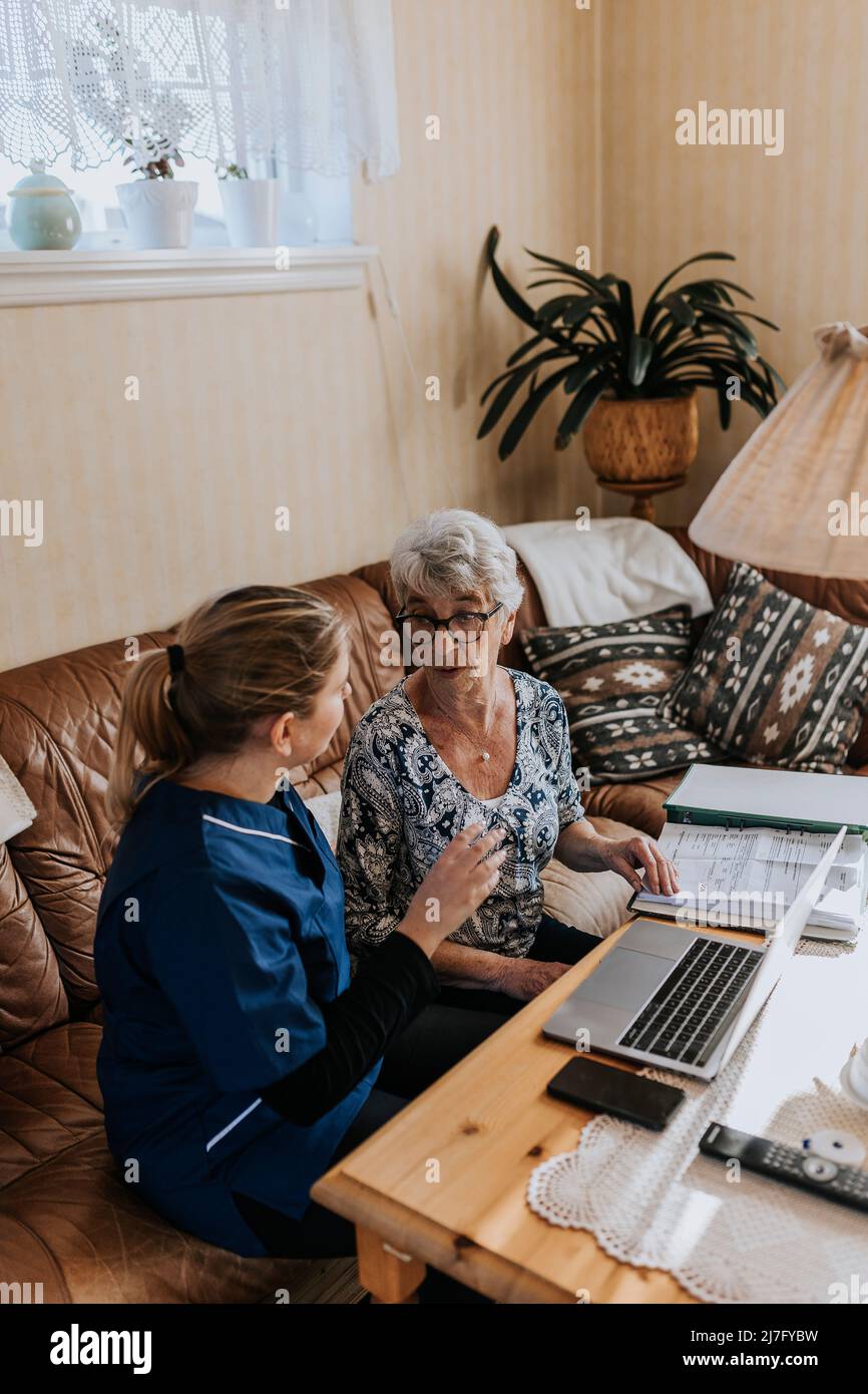 Home caretaker helping senior woman with bills Stock Photo - Alamy