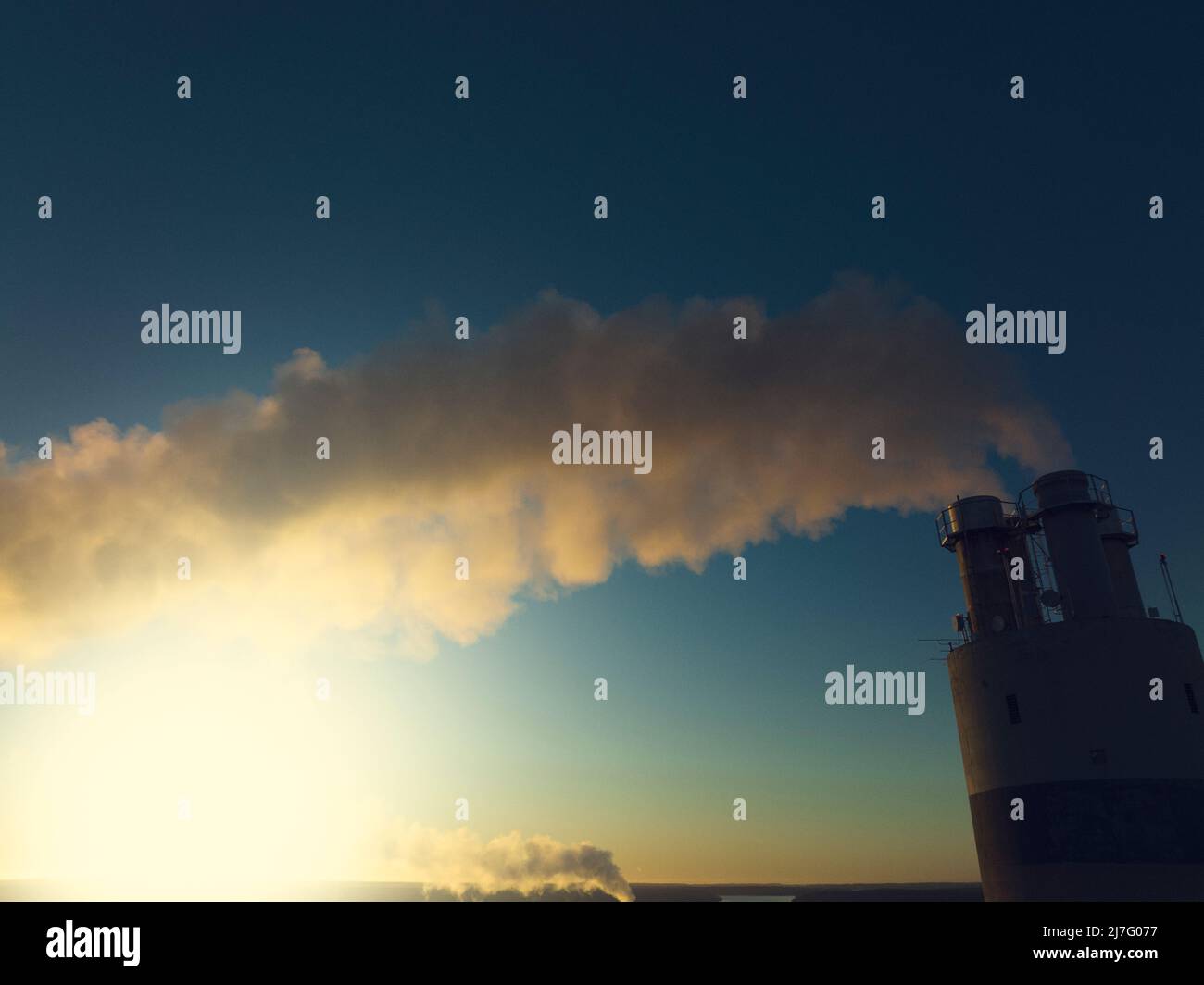 Smoke stack emitting smoke into blue sky Stock Photo - Alamy