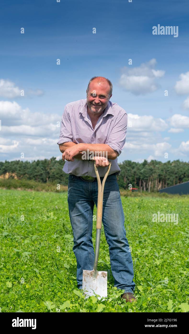 Farmer stood in his field leaning on a spade. Durham, UK Stock Photo ...