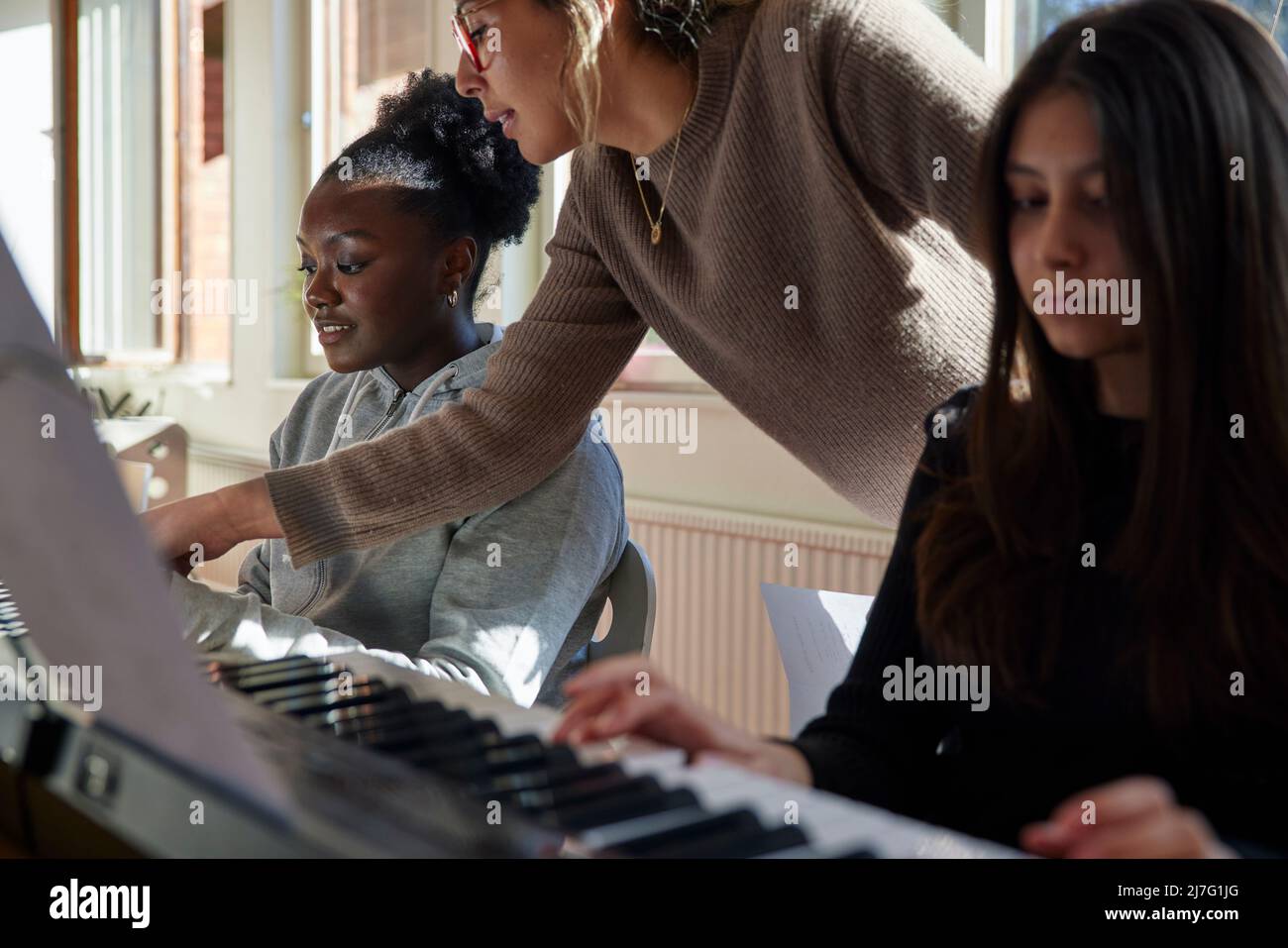 Teenage girls and teacher during keyboard lesson Stock Photo - Alamy