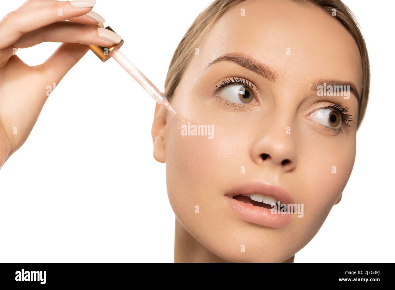 Close up beautiful young woman applying serum, oil on face on white ...