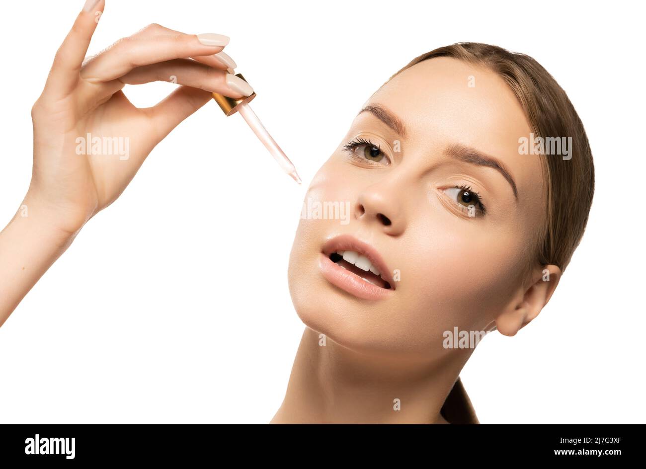 Close up beautiful young woman applying serum, oil on face on white ...