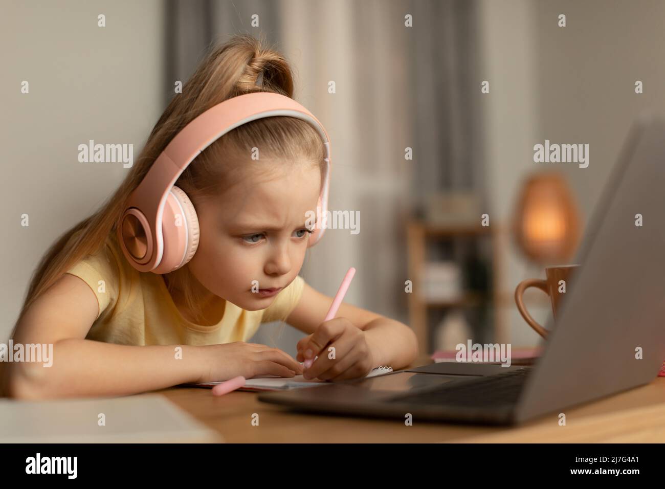 Little Girl Using Laptop Taking Notes Learning Online At Home Stock ...