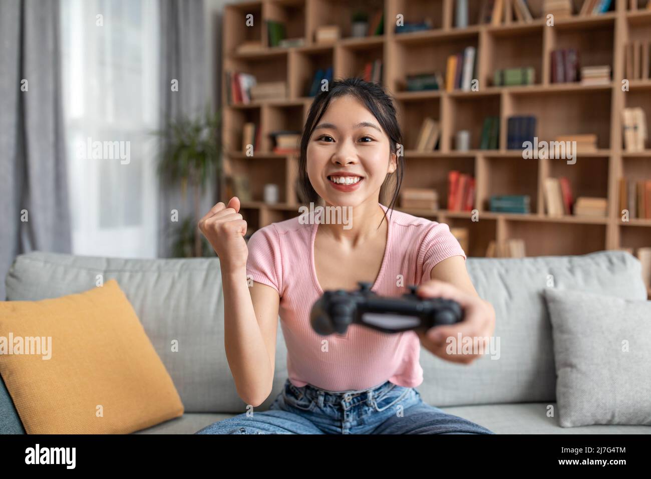 Happy korean lady with controller playing online video games and making ...
