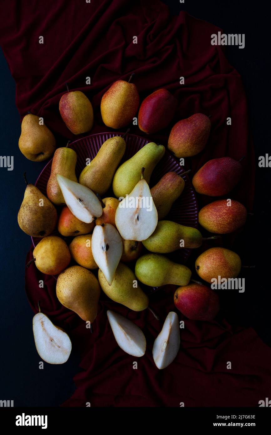Yellow and red juicy fragrant pears lie on a cherry plate on a dark ...