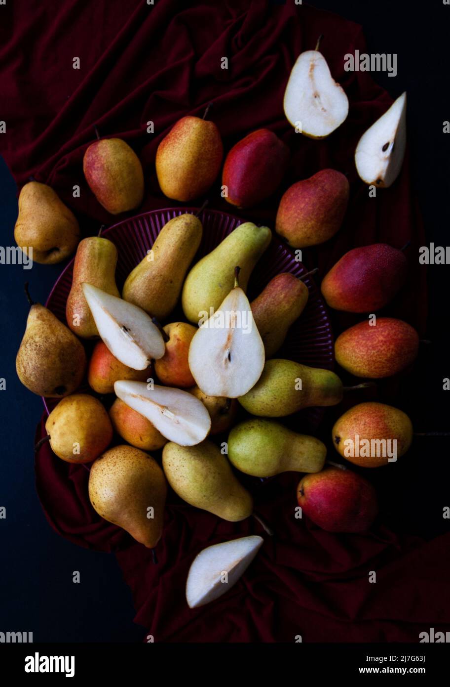 Yellow and red juicy fragrant pears lie on a cherry plate on a dark ...