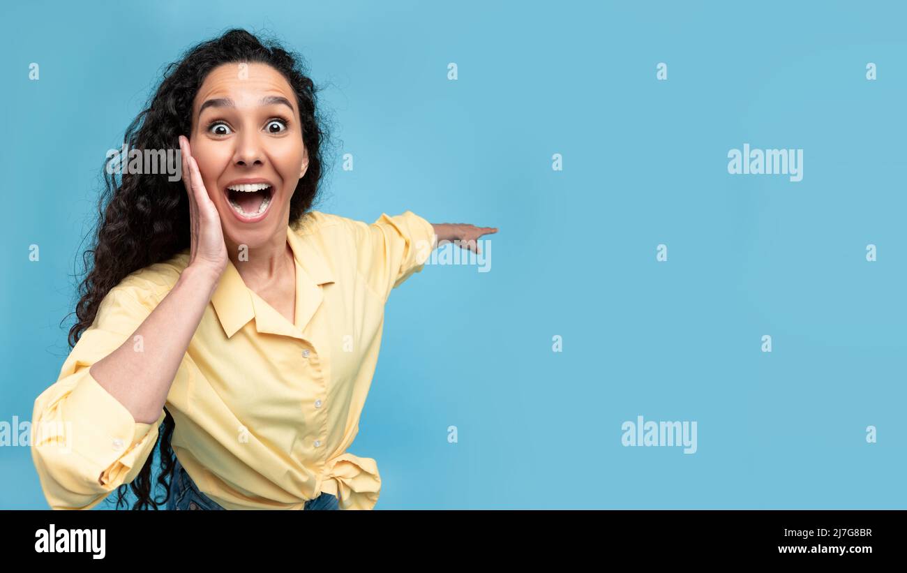 Excited woman pointing finger back at free copy space Stock Photo - Alamy
