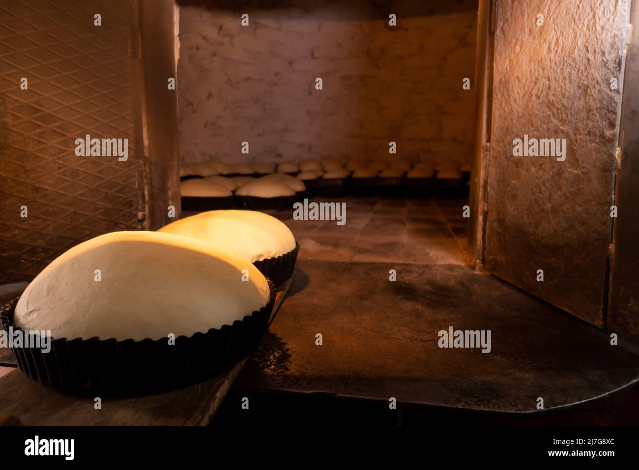 Close-up of bread dough in molds is sent to a shovel in a stone ...