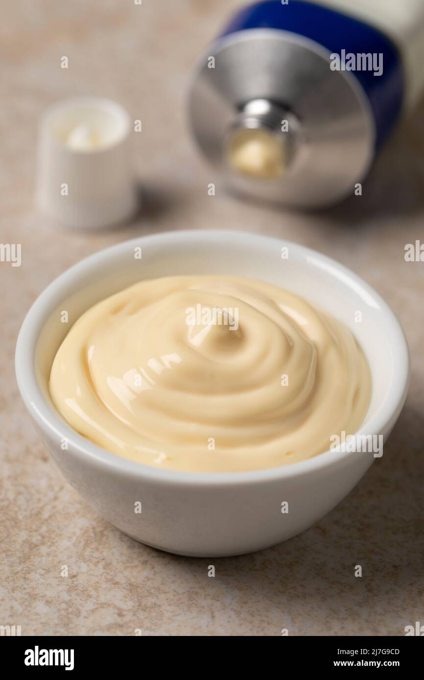 Bowl with Mayonnaise close up and a tube of mayonnaise in the ...