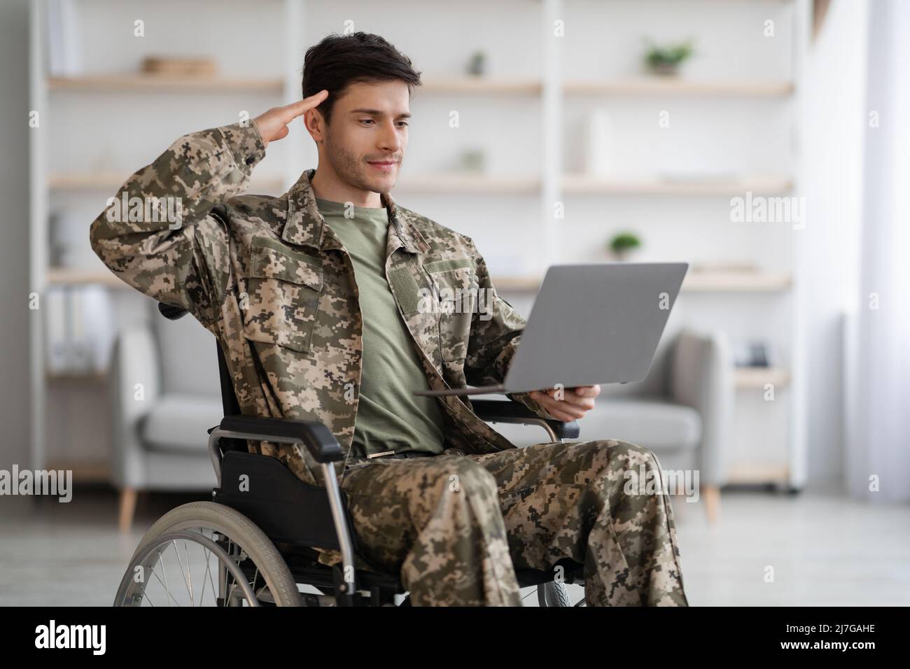 Patriotic veteran sitting in wheelchair, using laptop Stock Photo - Alamy