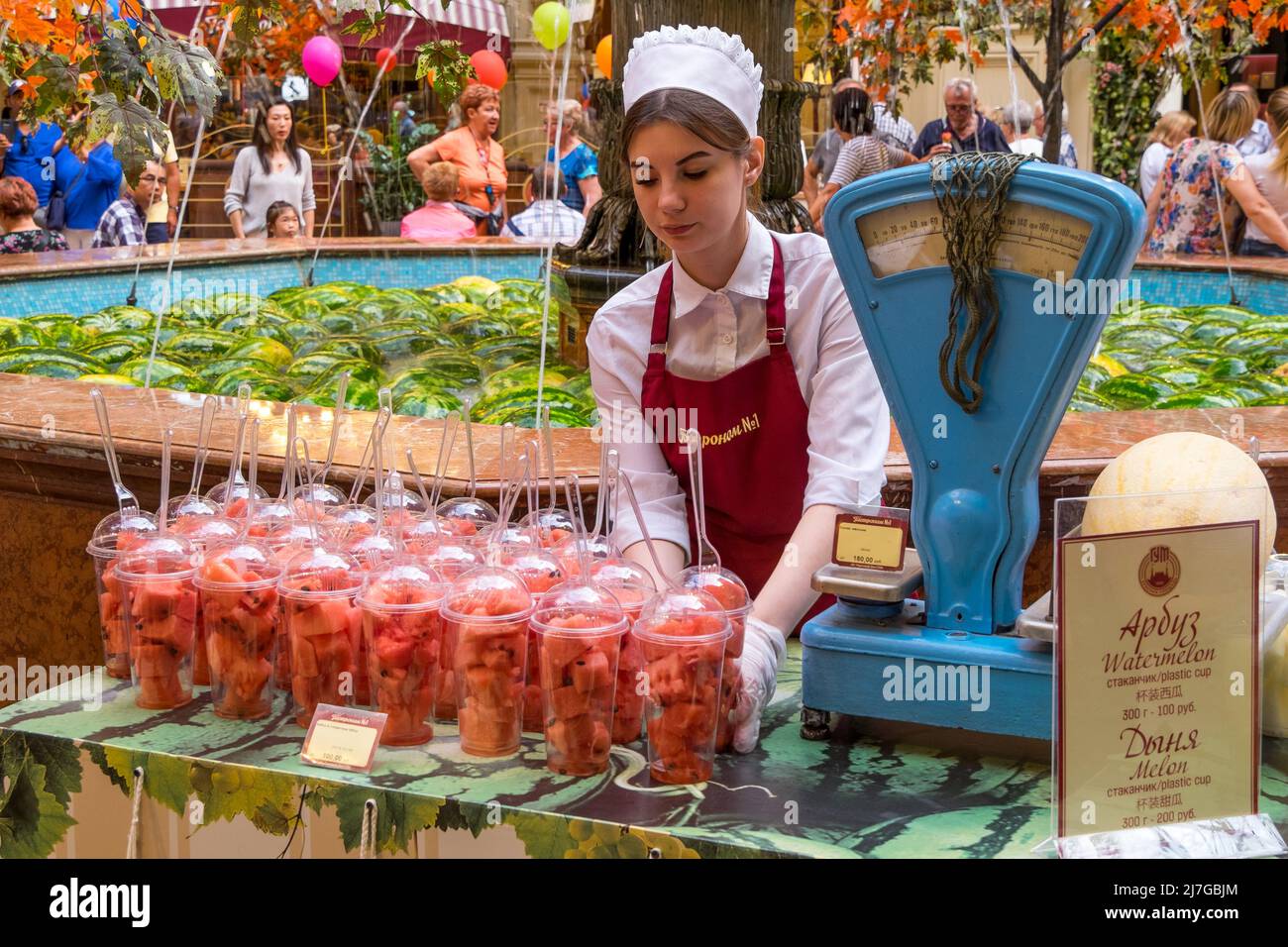 Young woman selling chopped fruit in the Gum shopping center of Moscow ...