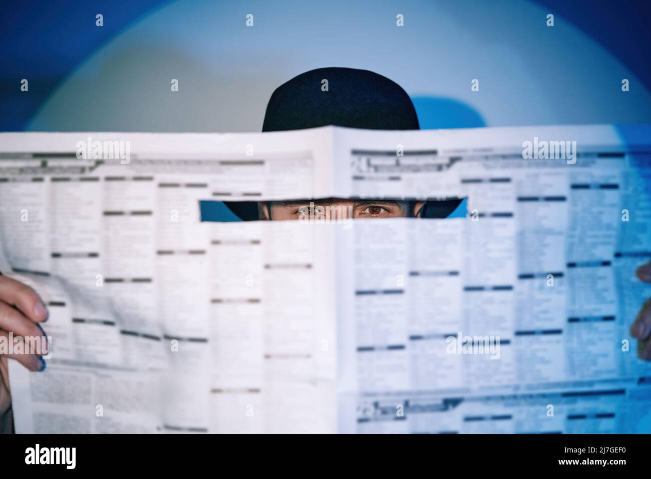 Man hiding watches through the newspaper in the spotlight on studio ...