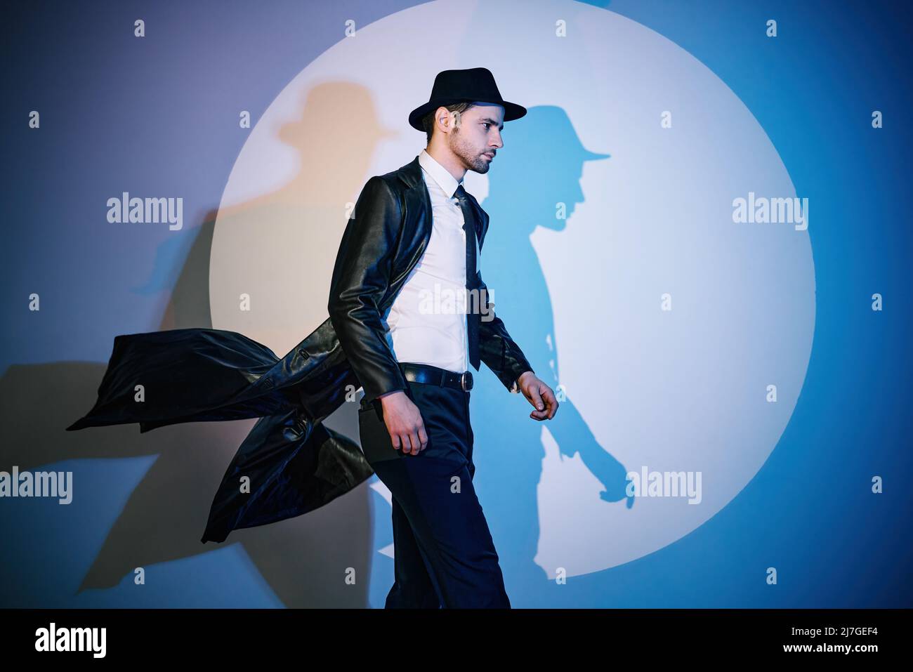 Handsome man in black coat and hat walking like superhero in the ...